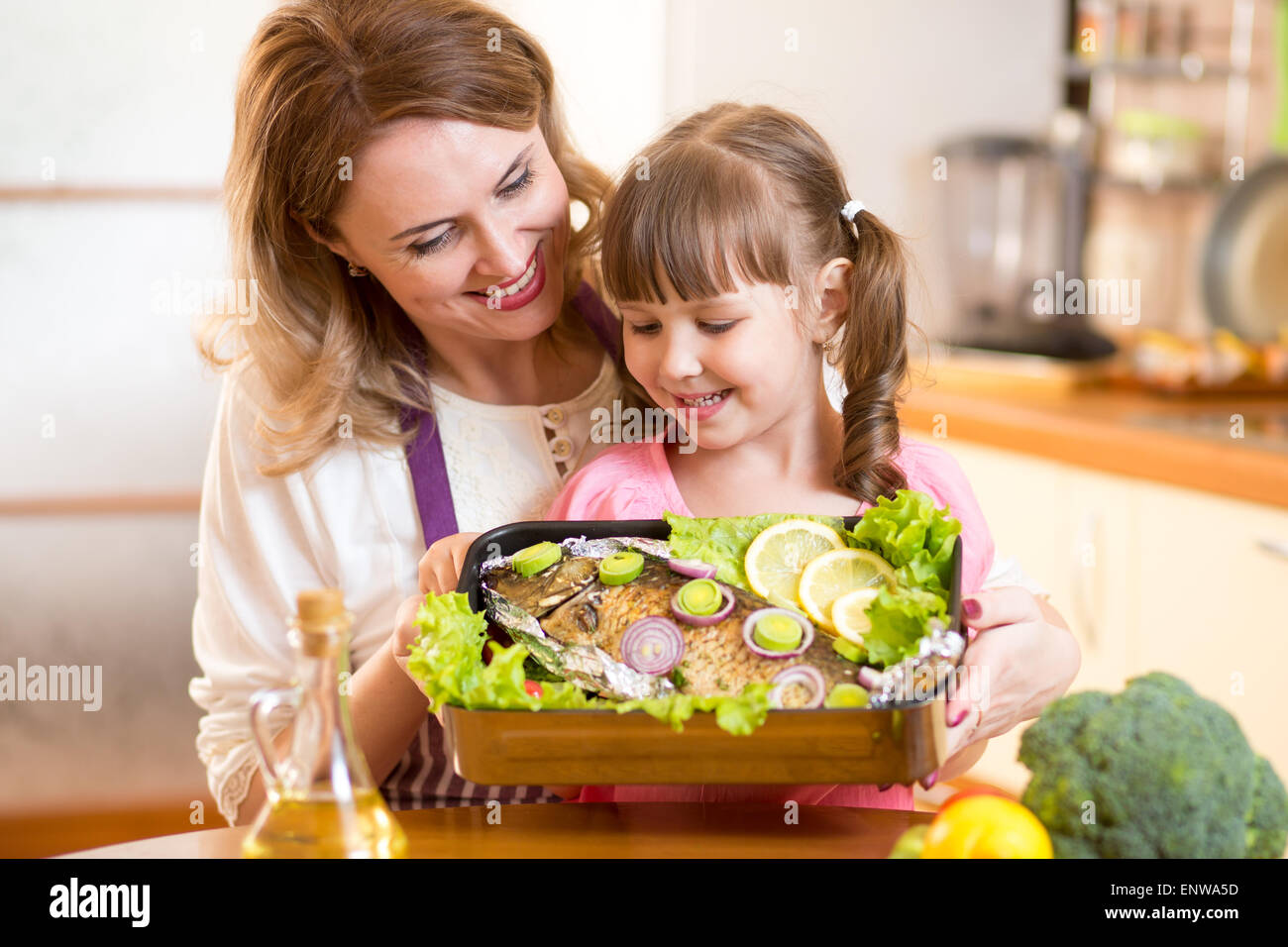 mother and child jolly look at prepared dish of fish Stock Photo - Alamy