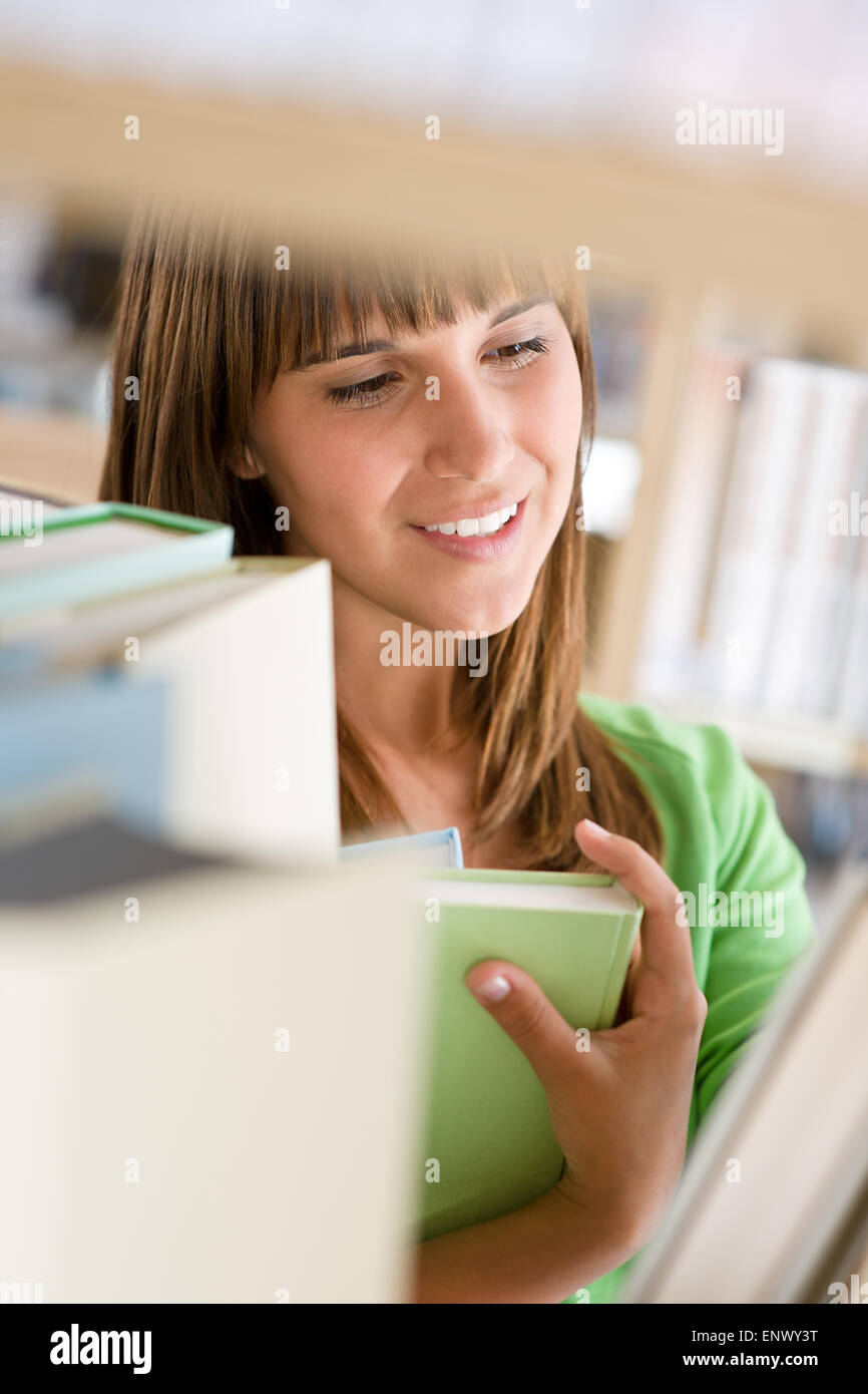 Student in library - cheerful woman stand by bookshelf Stock Photo - Alamy