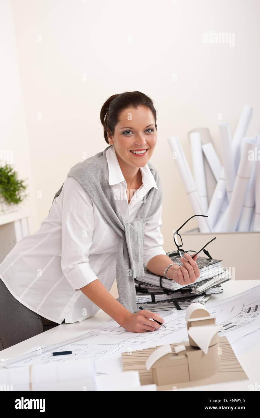 Smiling female architect with plans at the office Stock Photo - Alamy