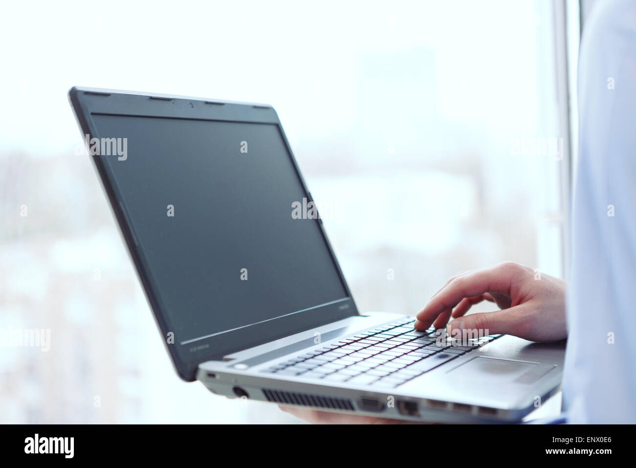 Man holding computer in front of window Stock Photo - Alamy