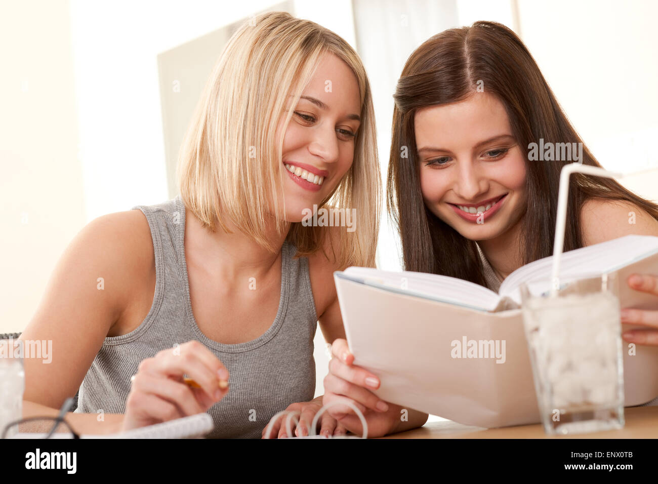 Student series - Two smiling girls watching book Stock Photo - Alamy
