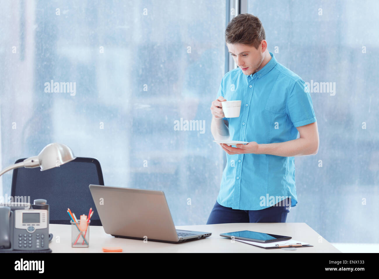Young businessman standing next to desk Stock Photo - Alamy