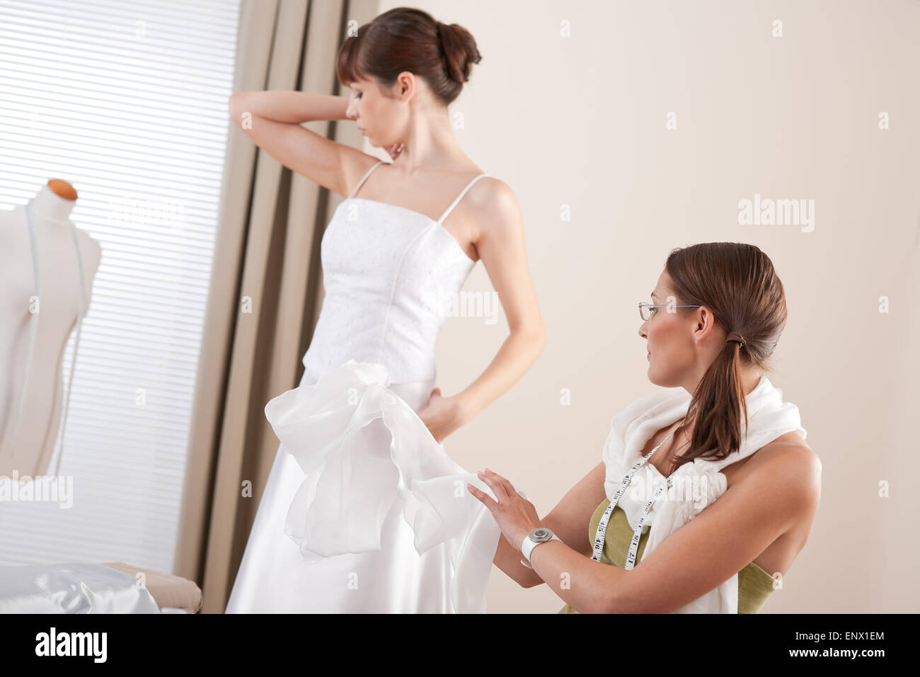 Fashion model fitting white wedding dress by designer Stock Photo - Alamy