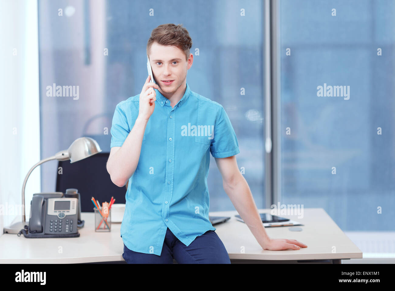 Businessman sitting on desk and talking per phone Stock Photo - Alamy