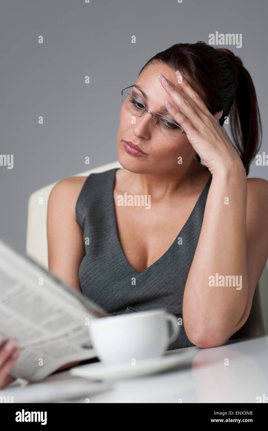 Thoughtful businesswoman read newspaper at office Stock Photo - Alamy