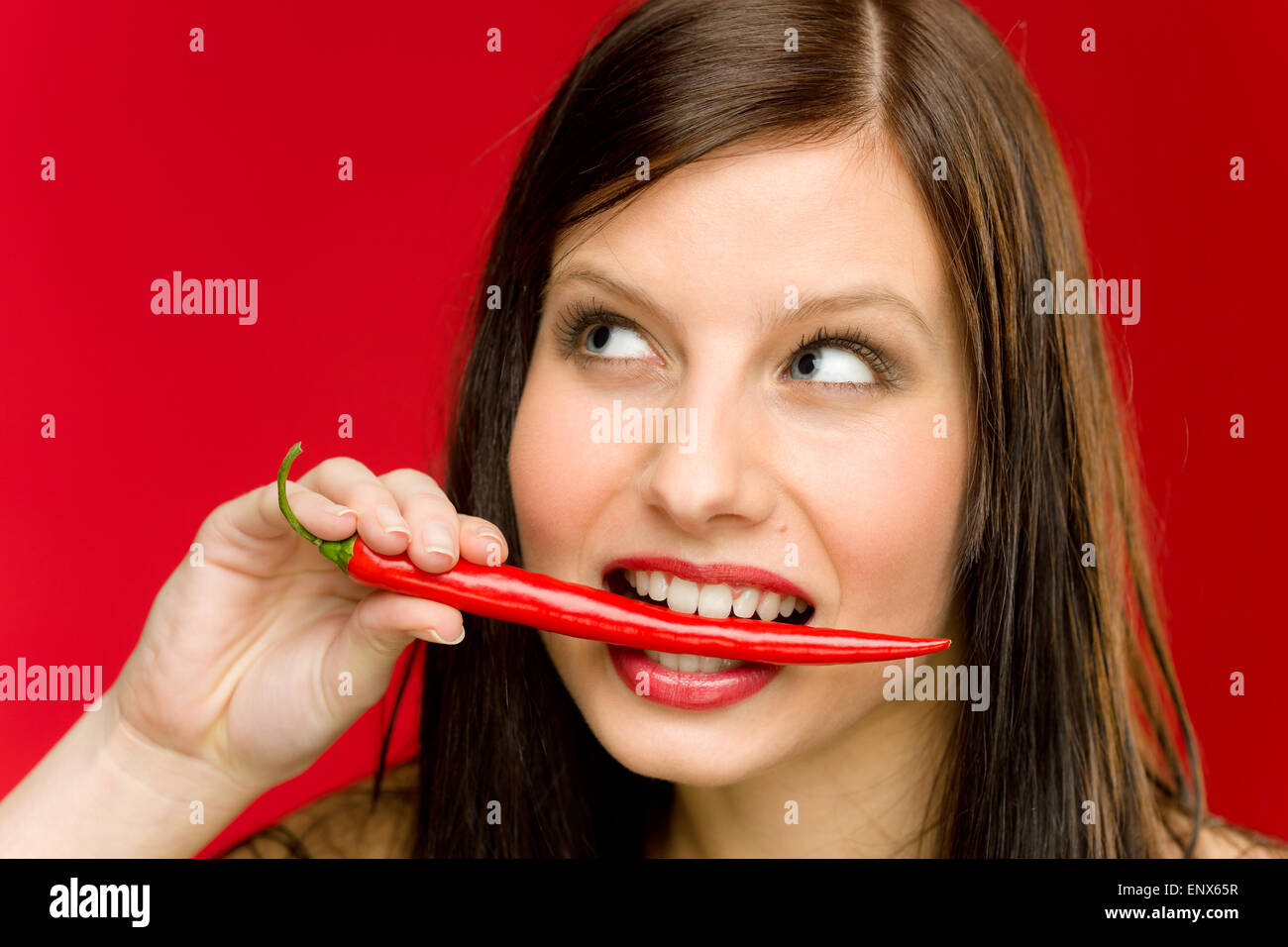 Chili pepper - portrait young woman bite red spicy Stock Photo - Alamy