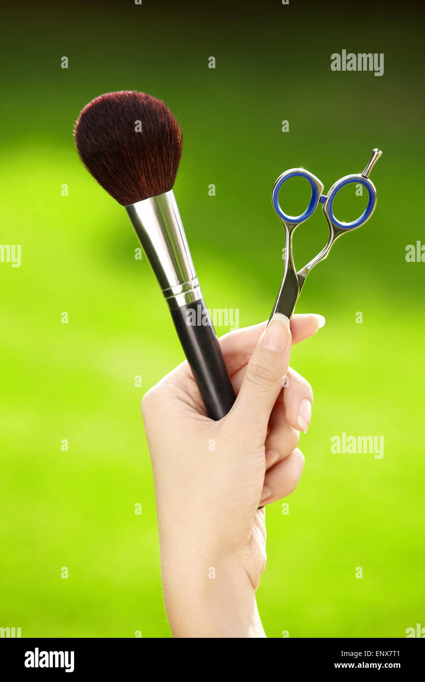 Hand with brash and scissors on green background Stock Photo - Alamy