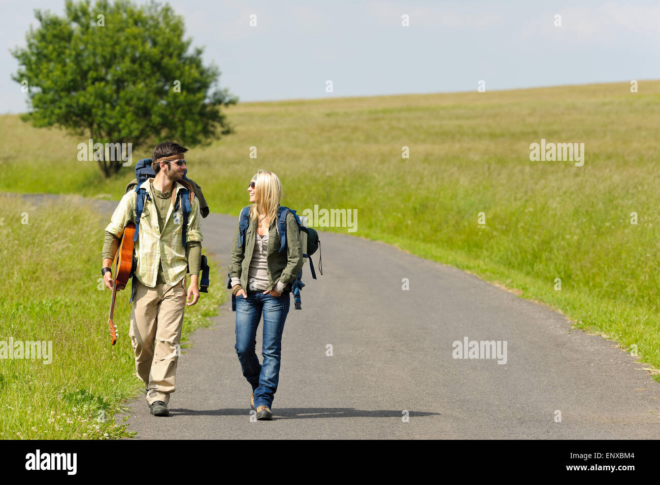 Hiking young couple backpack tramping asphalt road Stock Photo - Alamy