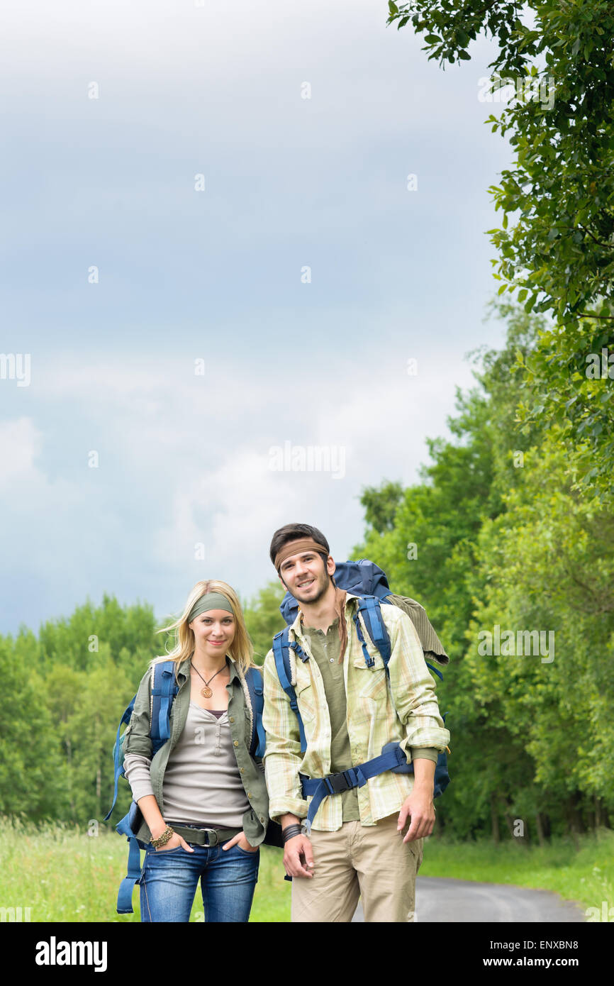 Hiking young couple backpack asphalt road countryside Stock Photo - Alamy