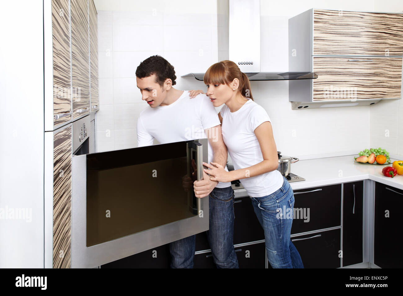 The surprised young couple looks in an oven on kitchen Stock Photo - Alamy