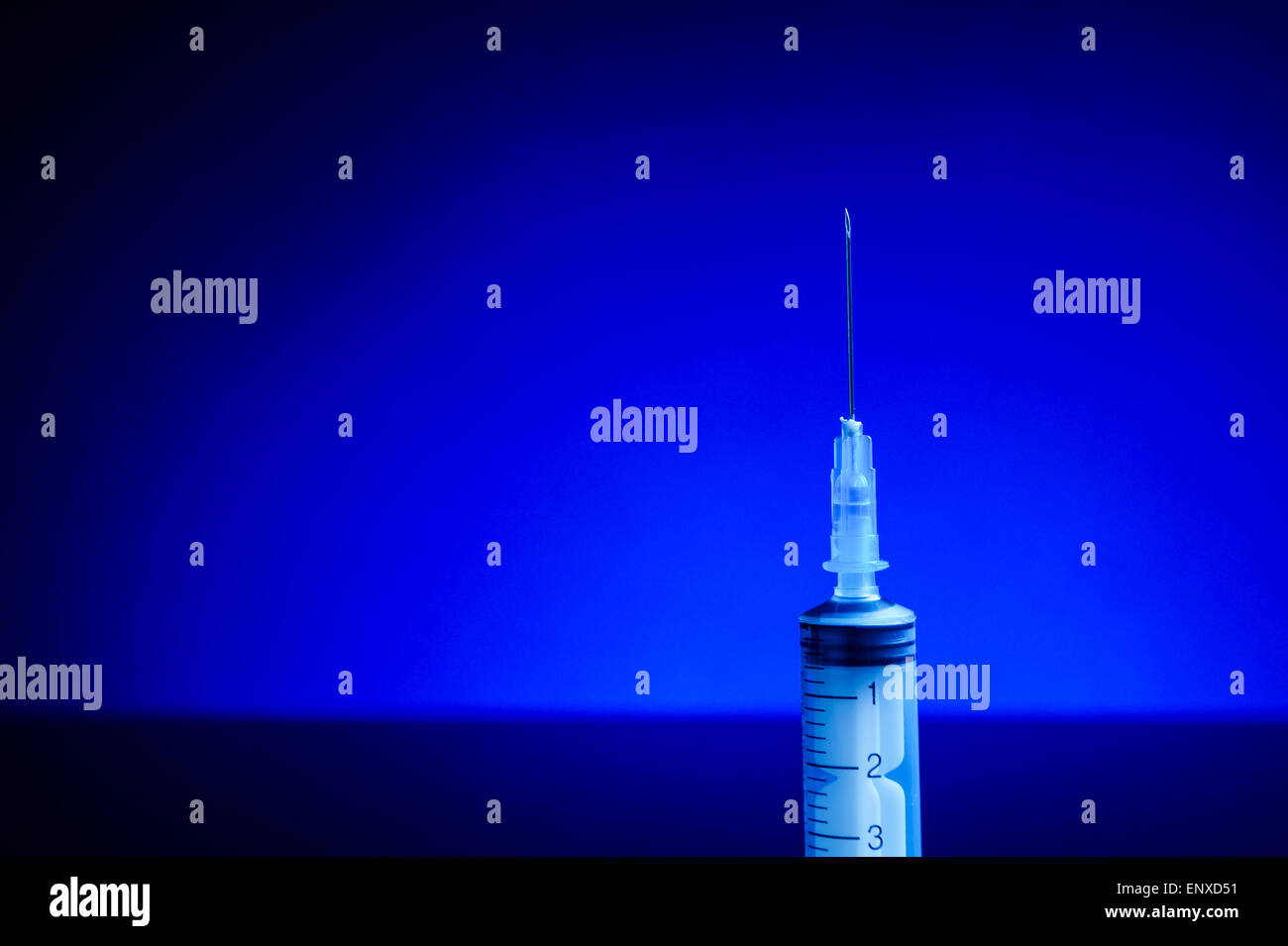 Syringe with needle, upright standing, isolated with background light ...