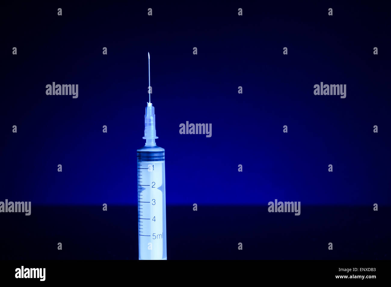 Syringe with needle, upright standing, isolated with background light ...