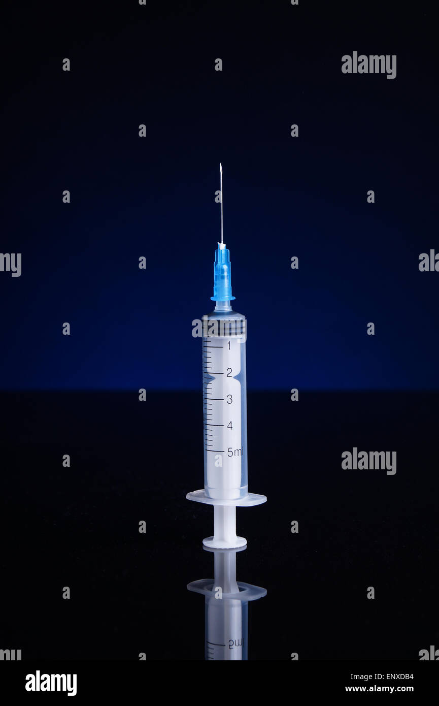 Syringe with needle, upright standing, isolated with background light ...