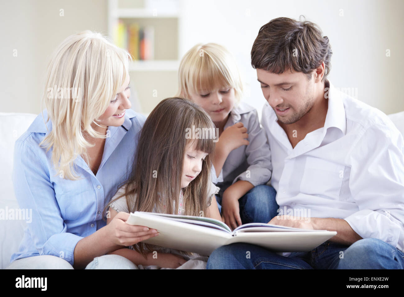 Young parents reading a book for young children Stock Photo - Alamy