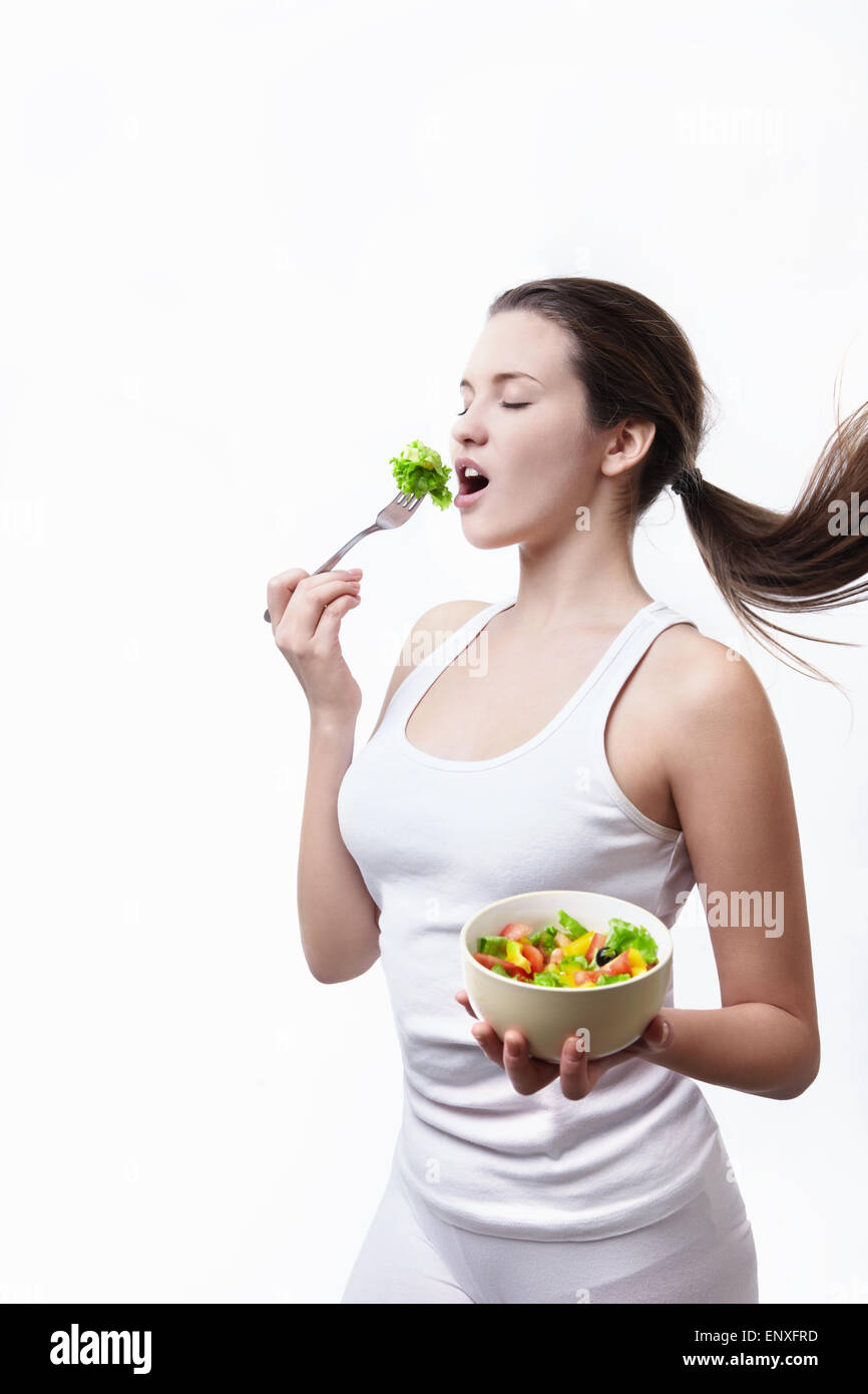 Attractive running girl eating salad on a white background Stock Photo ...