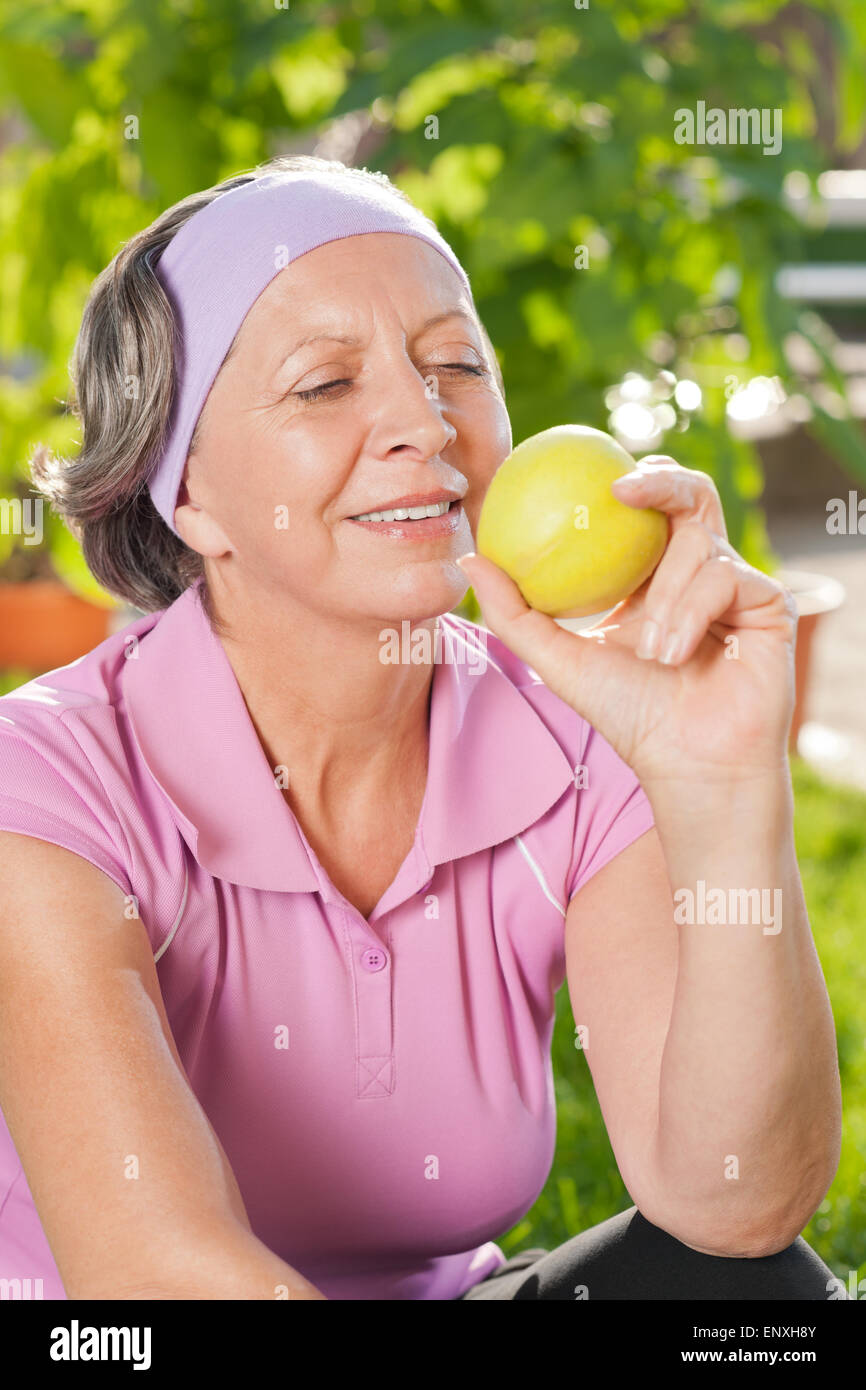 Senior sportive woman smile eat apple outdoor Stock Photo - Alamy