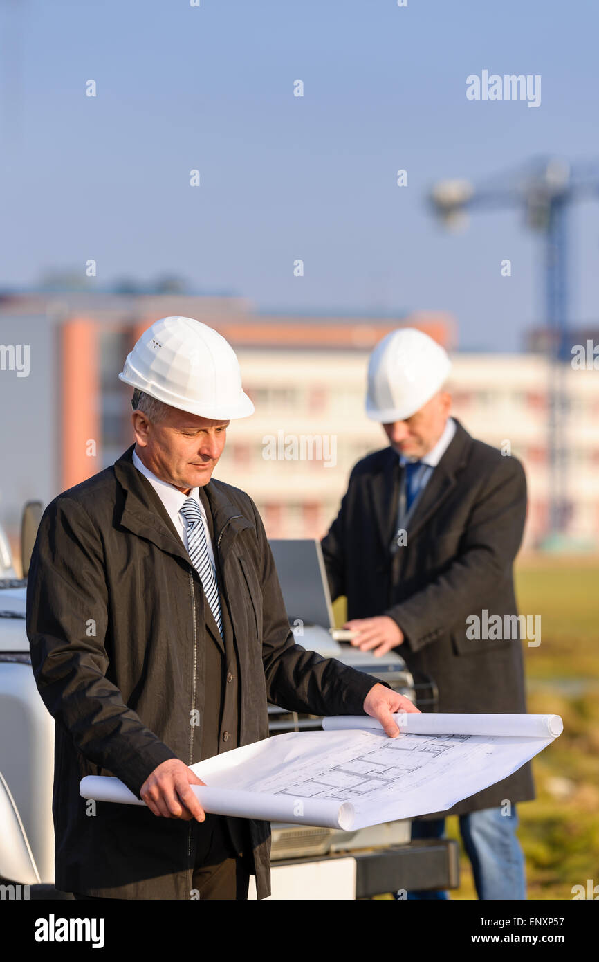 Two architects at construction site review plans Stock Photo - Alamy