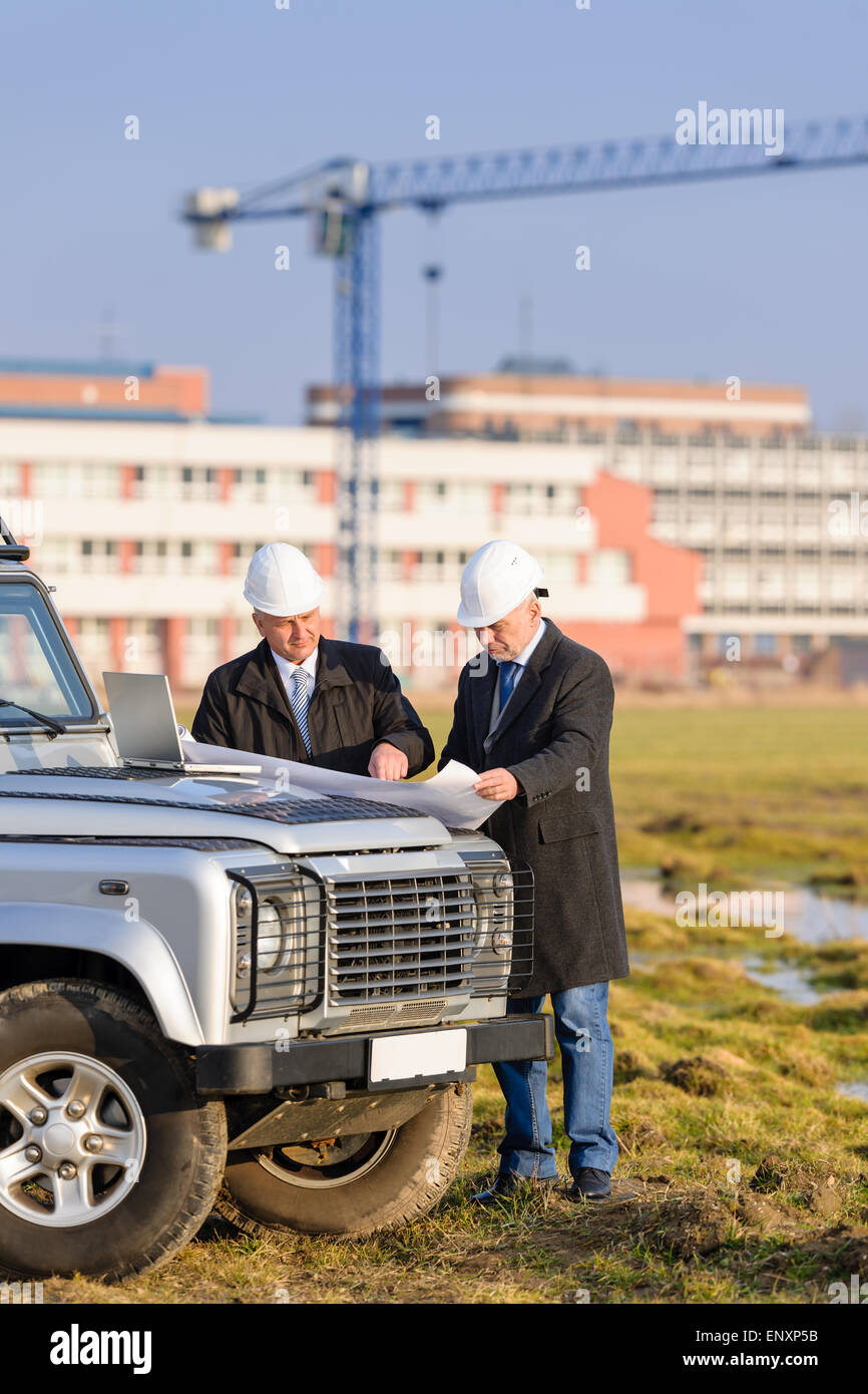 Two architects at construction site review plans Stock Photo - Alamy
