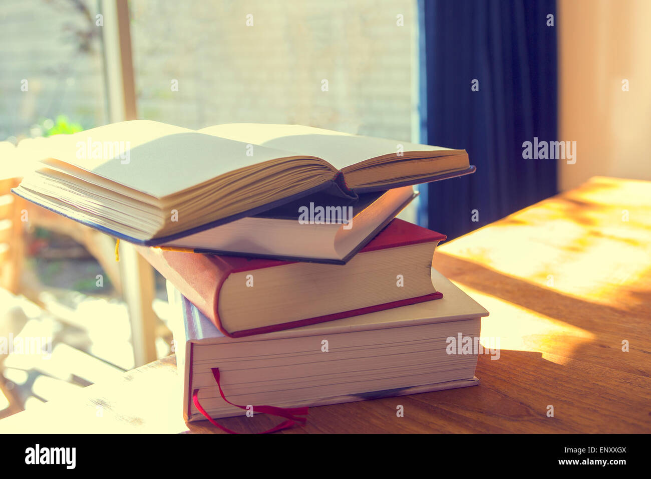 Stack of books on table in sunlight Stock Photo - Alamy