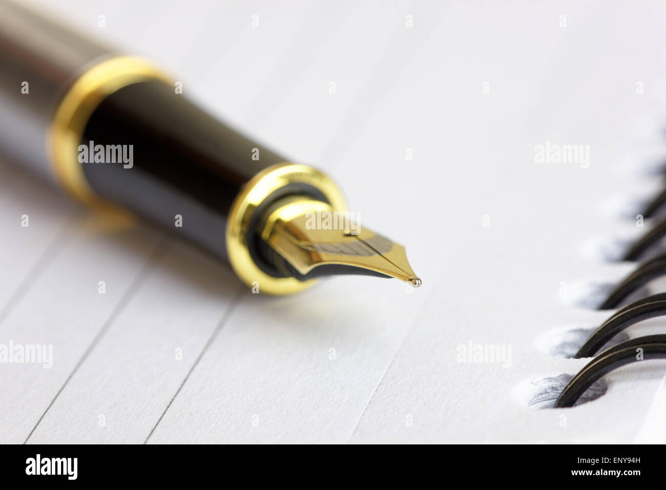 Close up of a gold fountain pen nib on a spiral bound note pad, with ...