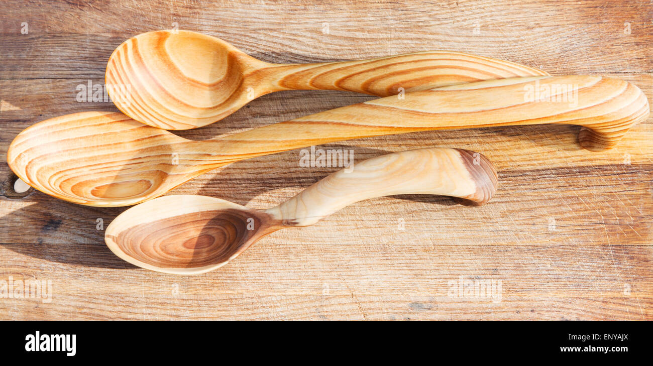 three carved wooden spoons on cutting board Stock Photo - Alamy