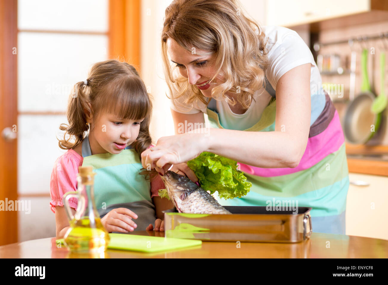 child girl with mom cooking fish in the kitchen Stock Photo - Alamy