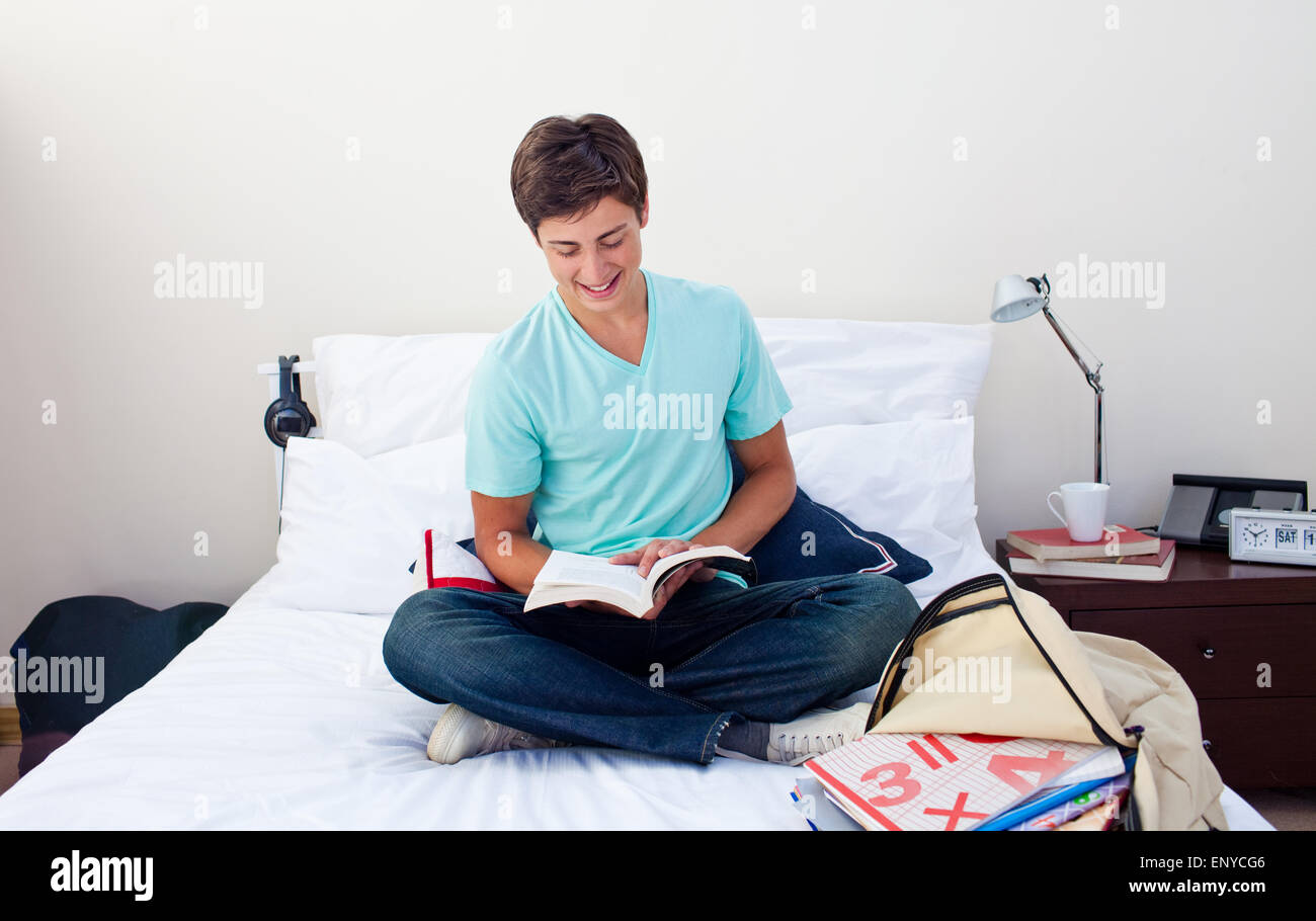 Smiling teenager reading a book in his bedroom Stock Photo - Alamy