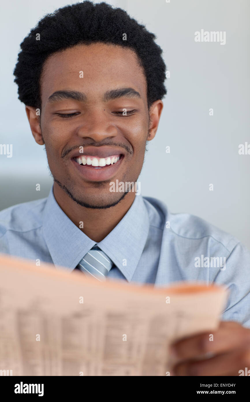Smiling Afro-American businessman reading a newspaper Stock Photo - Alamy