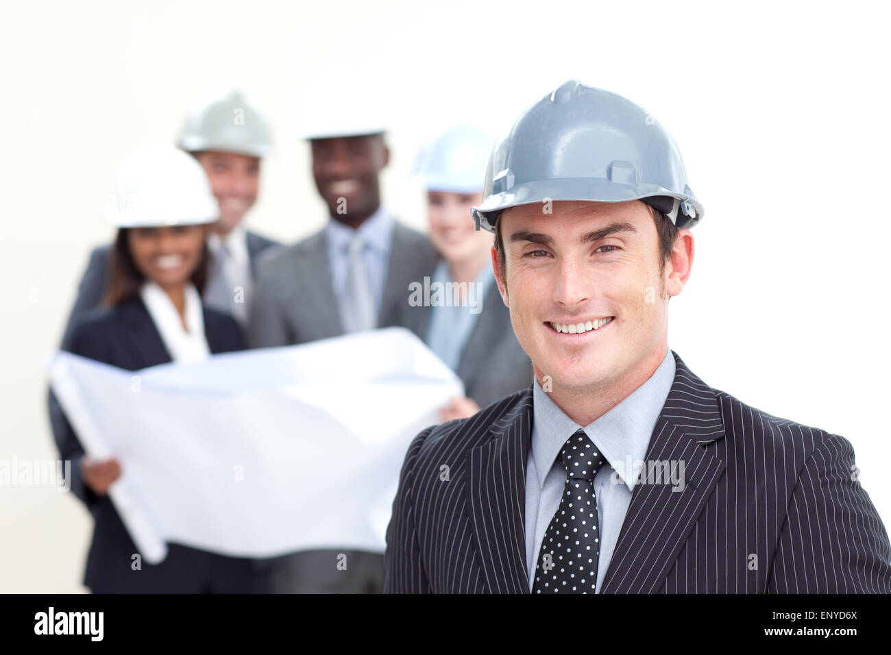 Attractive male architect with his team in the background smiling at ...