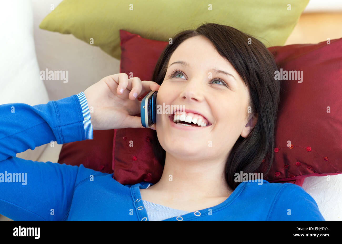 Happy teen girl talking on phone lying on a sofa Stock Photo - Alamy
