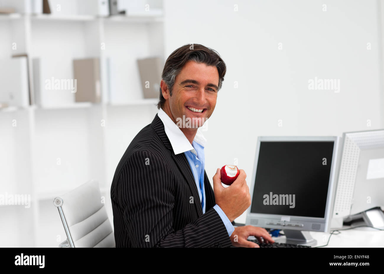 Businessman eating a fruit at work Stock Photo - Alamy
