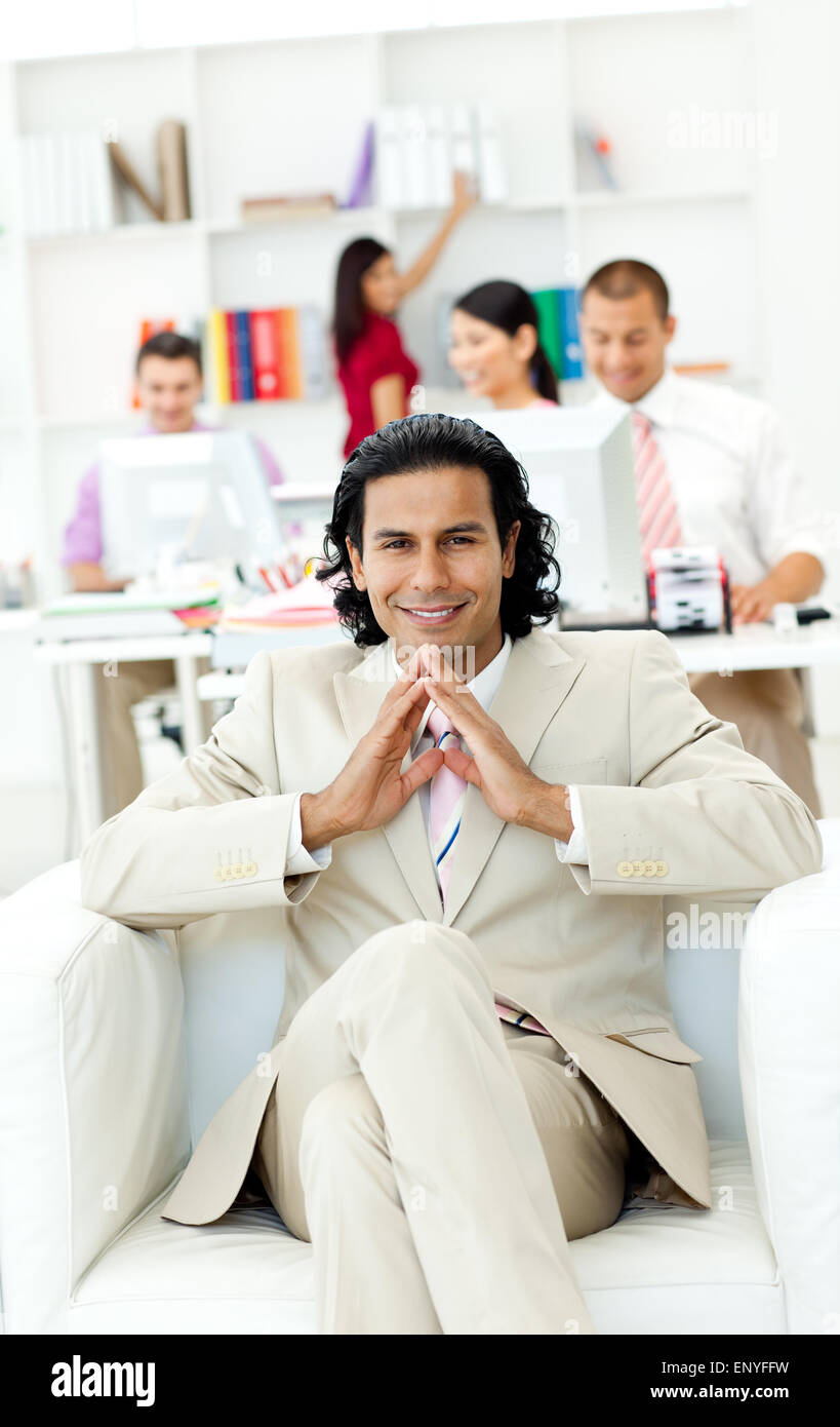 Cheerful manager sitting with his team in the background Stock Photo ... Cheerful manager sitting with his team in the background Stock Photo ...