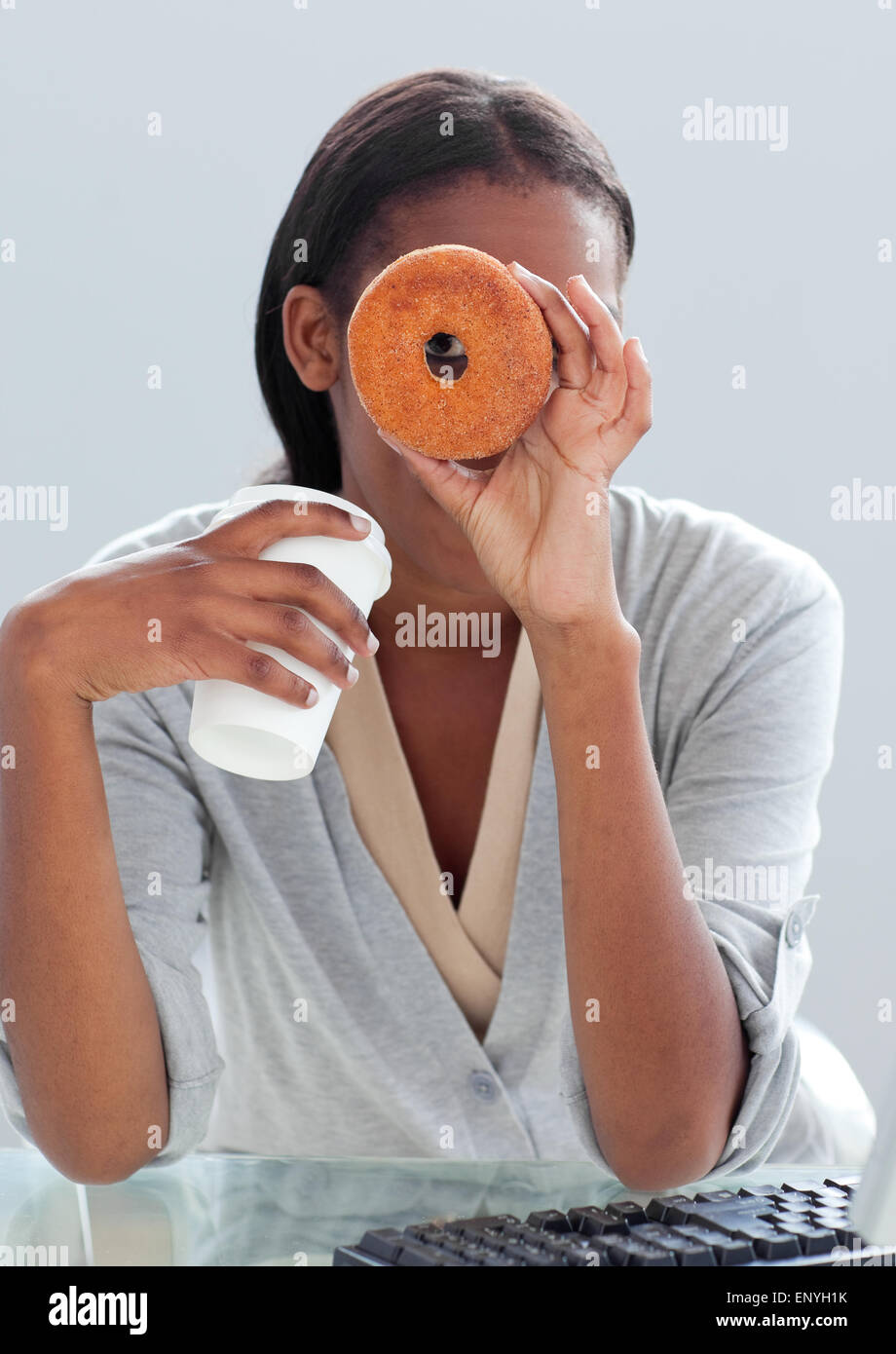 Young businesswoman eating a donut at her desk Stock Photo - Alamy