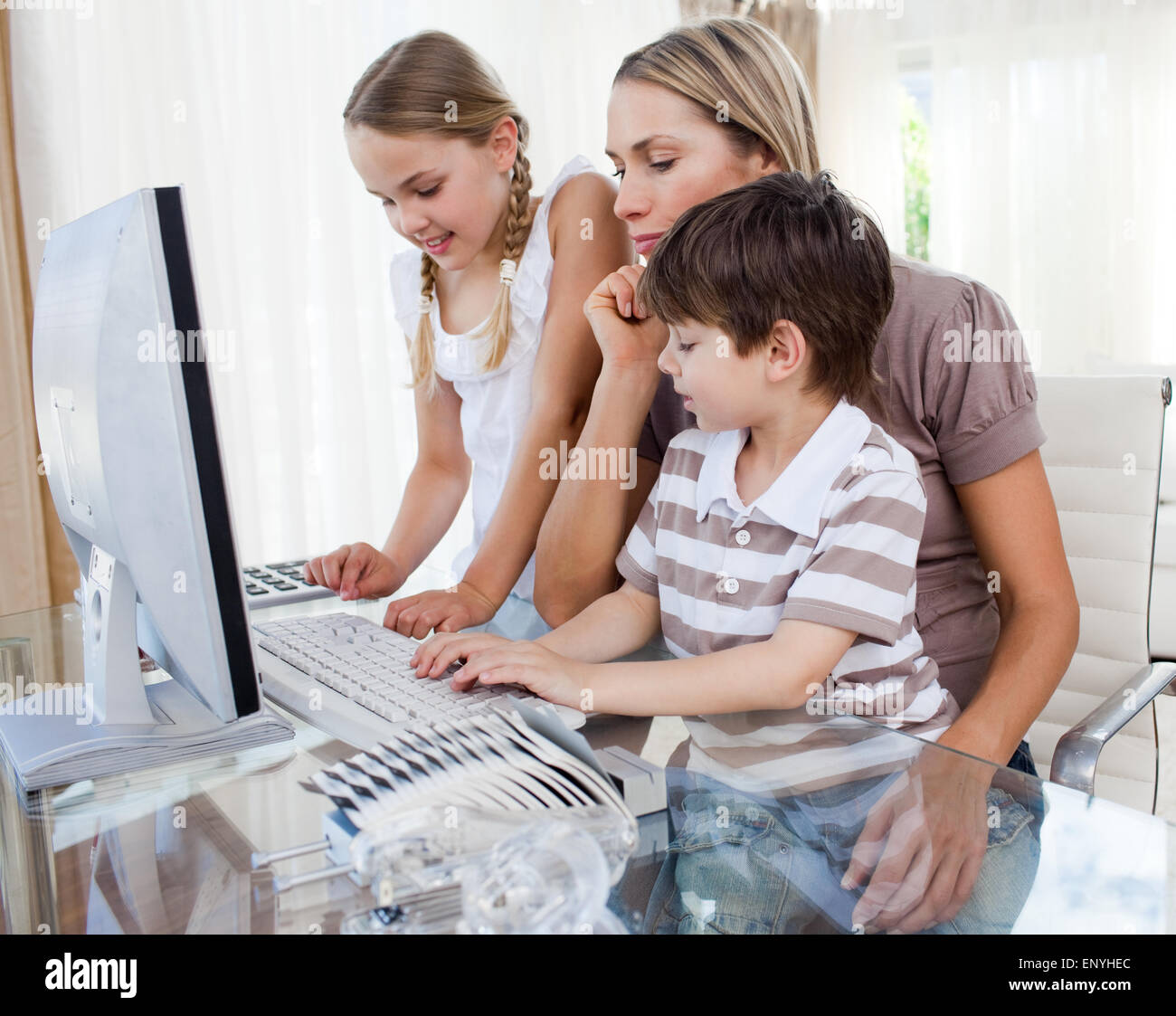 Attractive mother teaching her children how to use a computer Stock ...