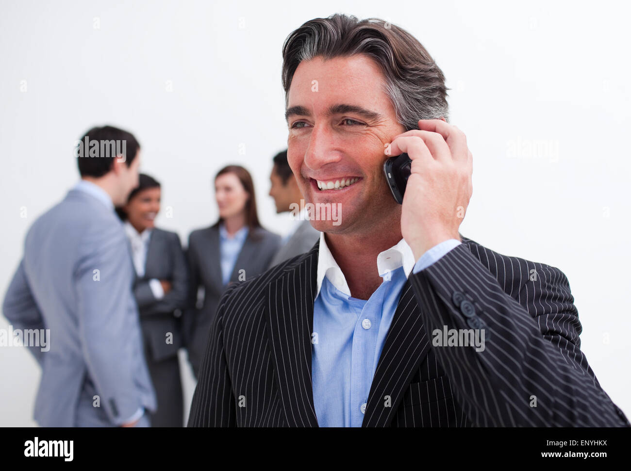 Attractive manager on phone with his team in the background Stock Photo ...