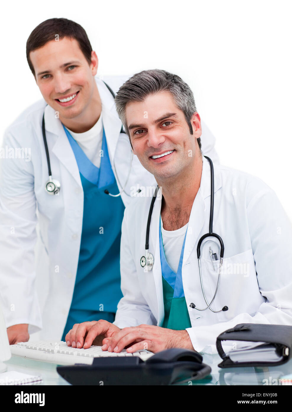 Two handsome male doctors working at a computer against a white ...