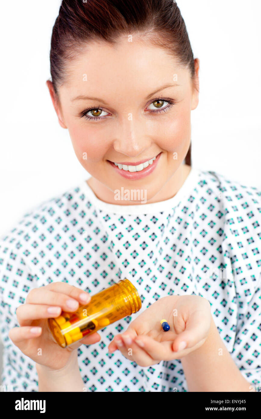 Smiling caucasian female patient holding pills against white background ...