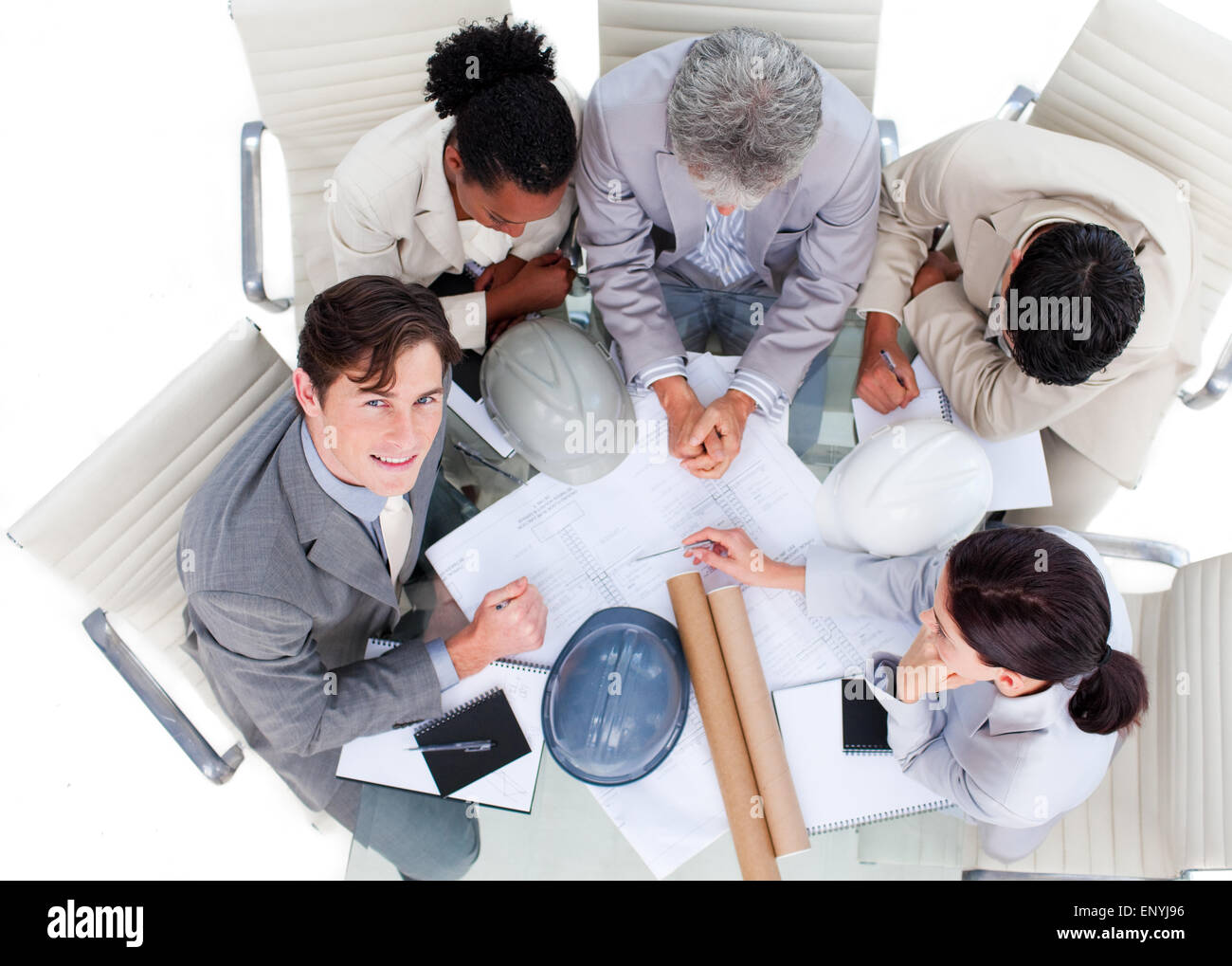 High angle of international architects studying blueprints in a meeting ...