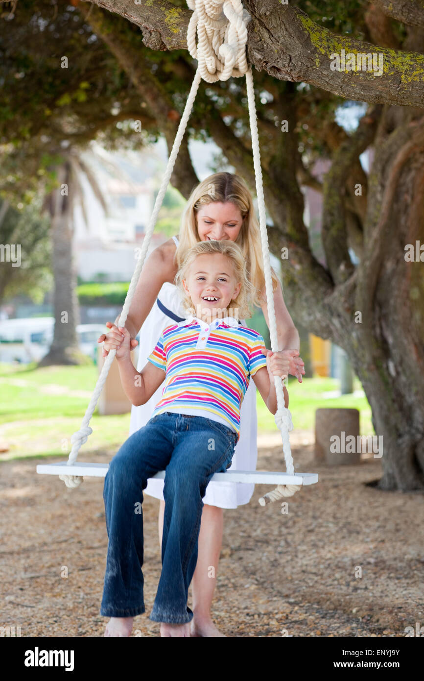 Happy mother pushing her daughter on a swing Stock Photo - Alamy