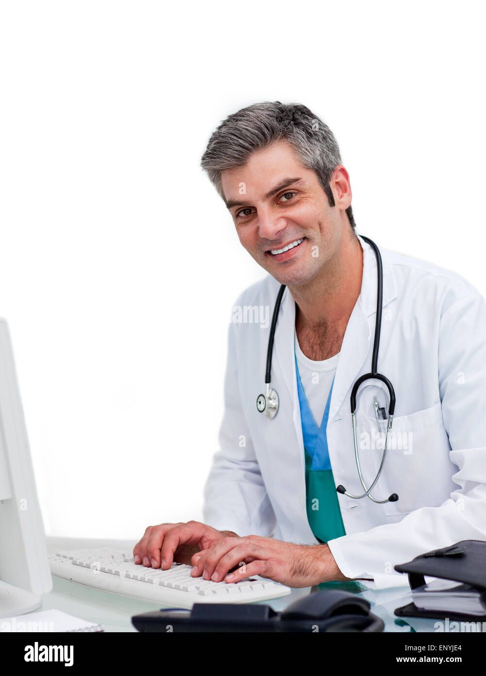 Mature male doctor working at a computer against a white background ...
