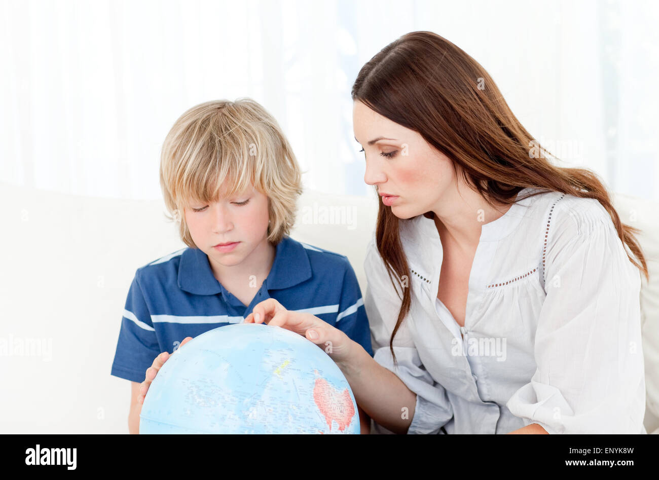 Captivated child looking at a terrestrial globe with his mother Stock ...