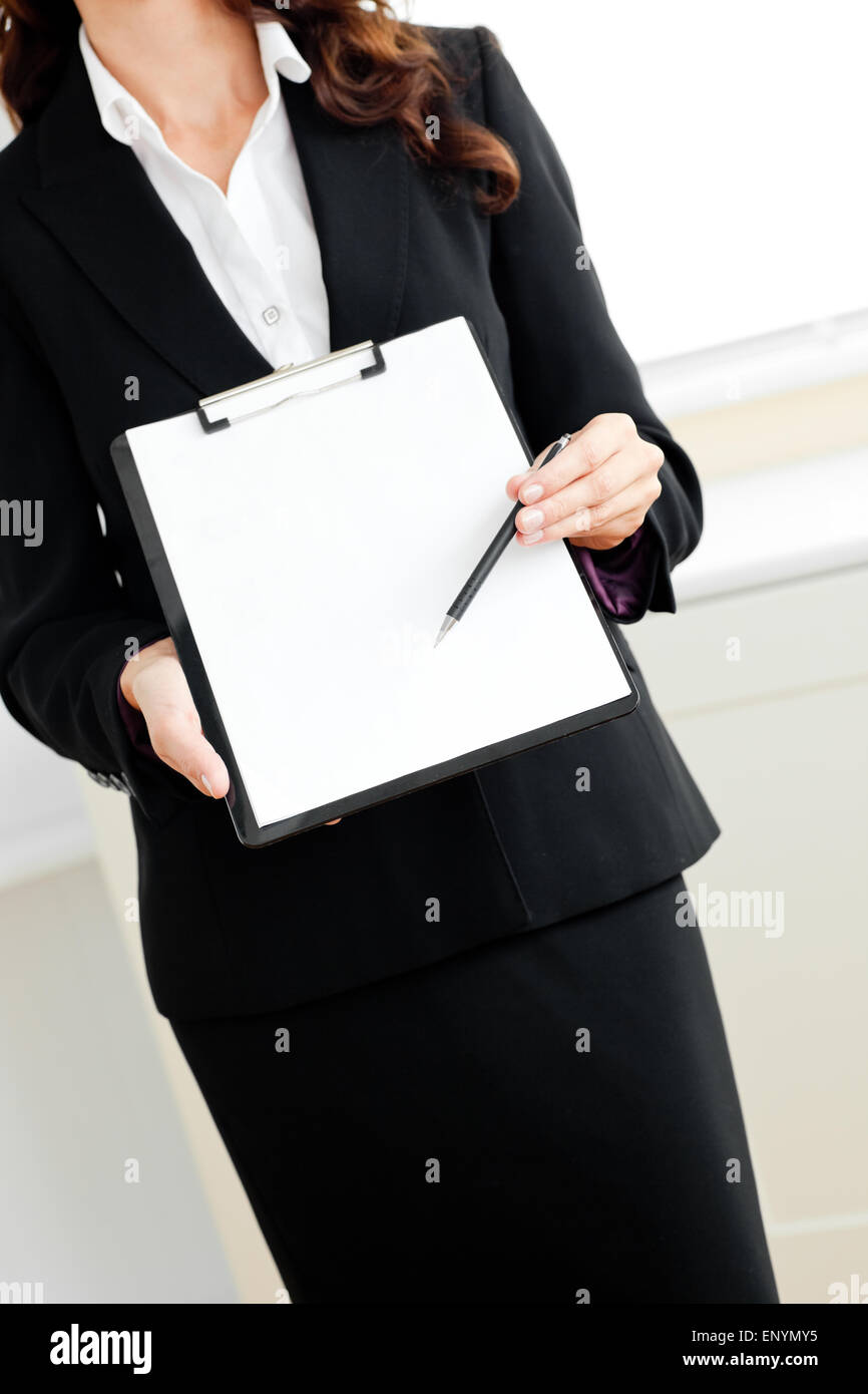 Close-up of an assertive businesswoman taking notes on her clipboard ...