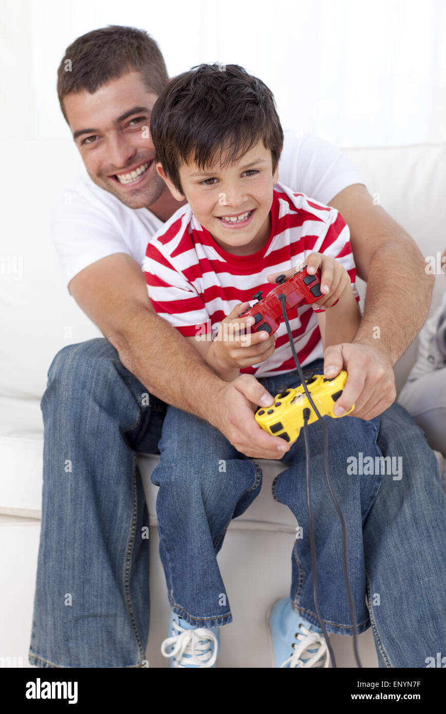 Smiling father and kid playing video games at home Stock Photo - Alamy