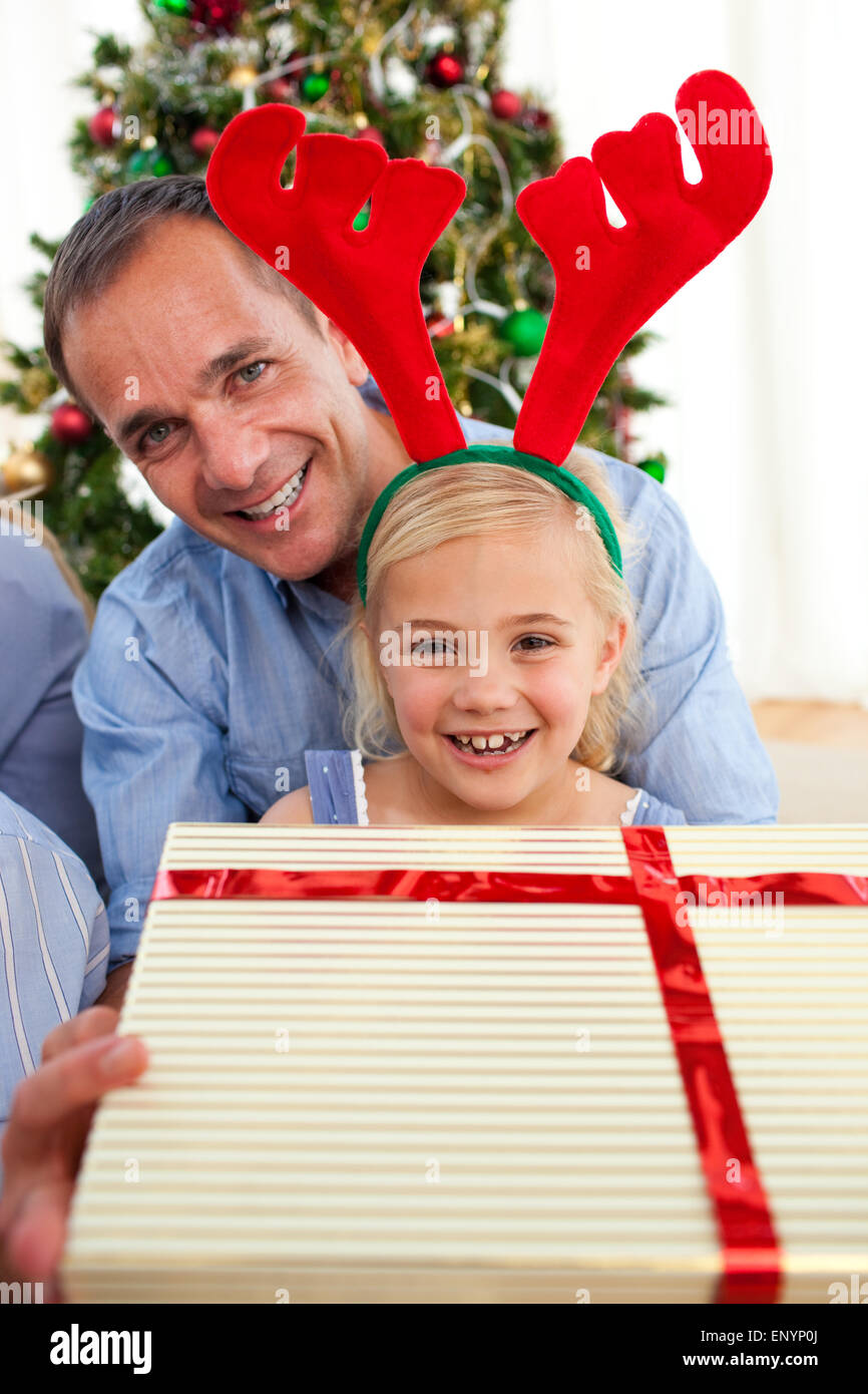Portrait of a smiling father and his daughter opening Christmas ...