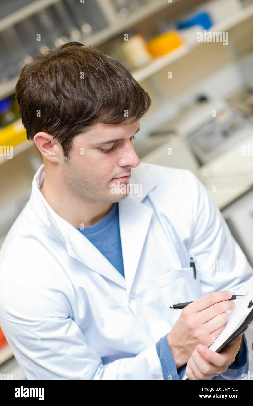 Concentrated scientist writing on a clipboard Stock Photo - Alamy