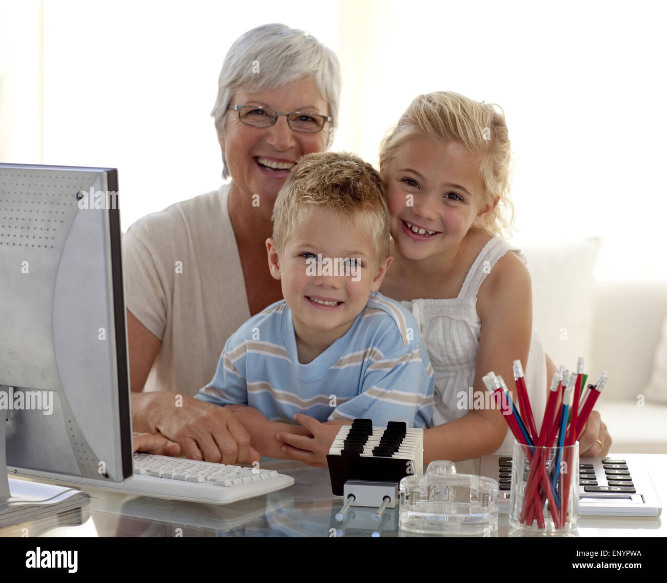 Happy children using a computer with their grandmother Stock Photo - Alamy