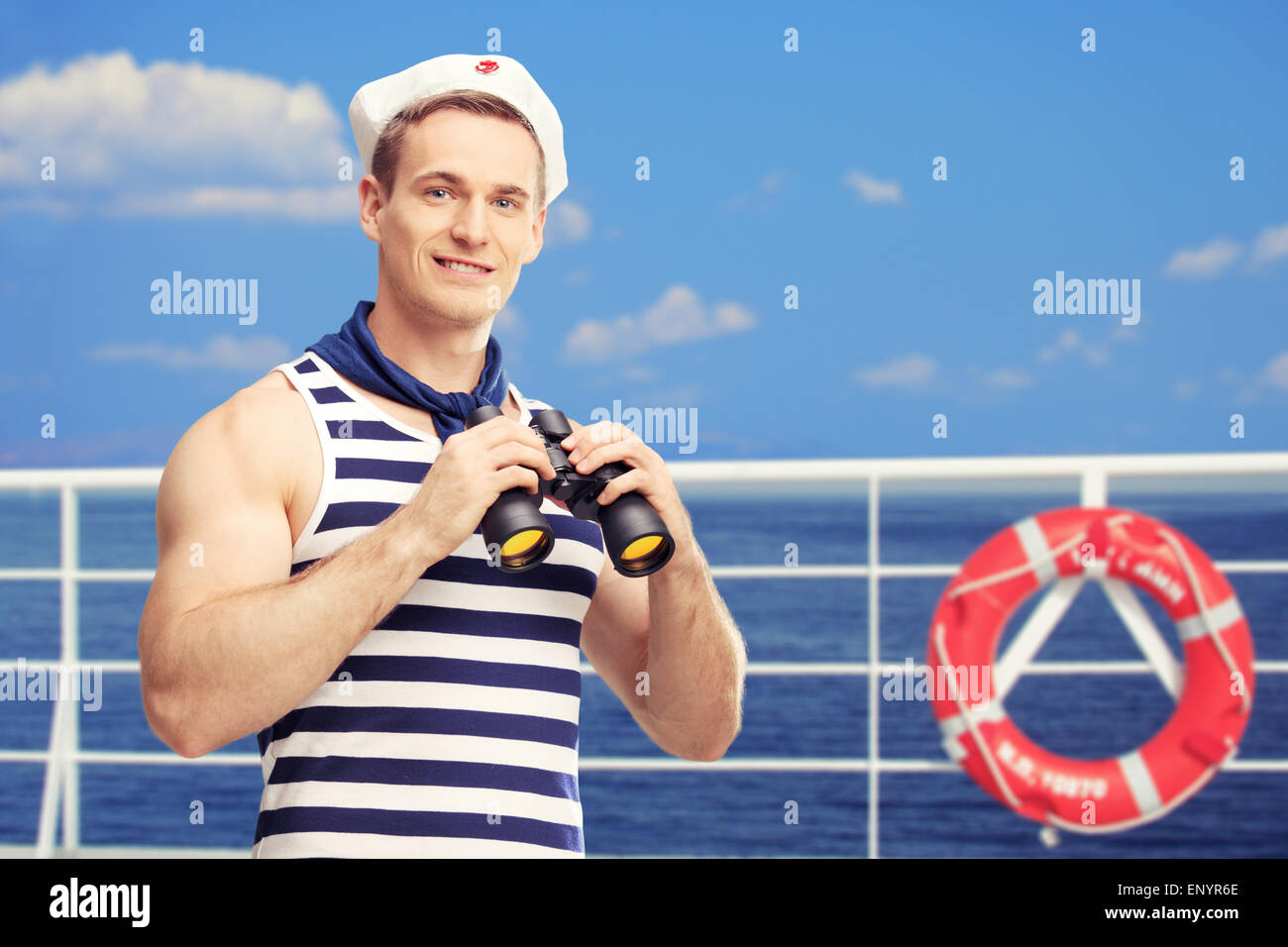 Young sailor holding binoculars and standing on a deck of a boat with ...