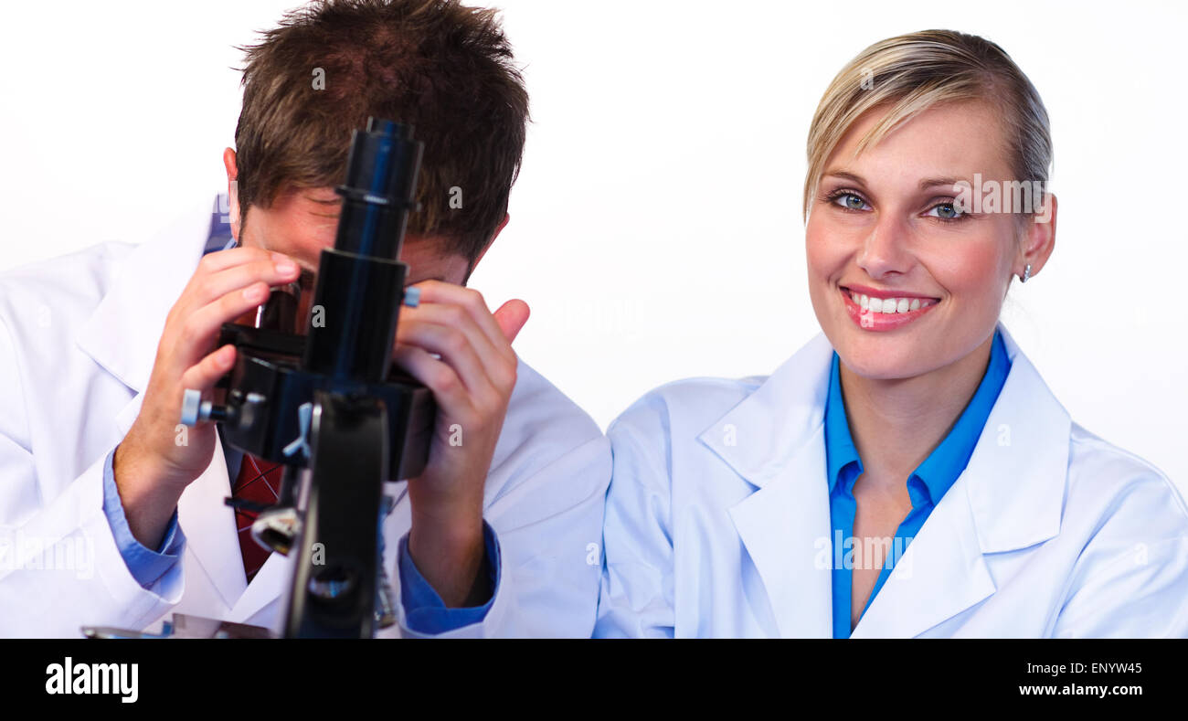 Woman smiling at the camera and male scientist looking through a ...