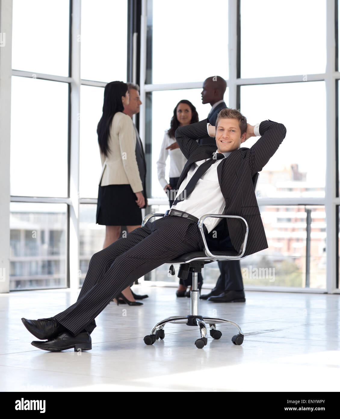 manager relaxing in office with team in background Stock Photo - Alamy