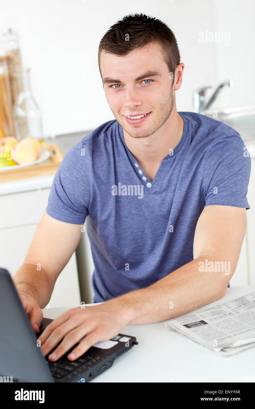 Handsome young man using his laptop looking at the camera in the ...